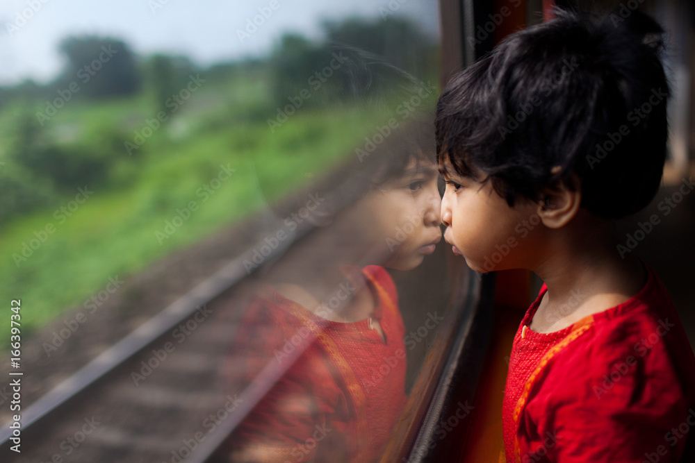 Little girl looking through the train window in a contemplative mood ...