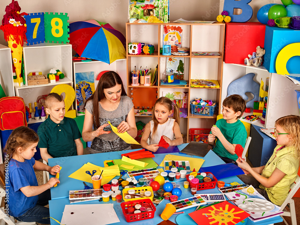 School children with scissors in kids hands cutting paper with teacher ...