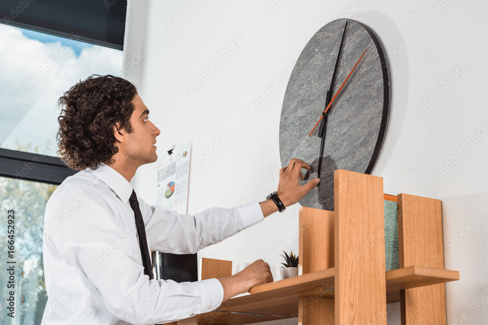 side view of young businessman setting time on clock in office Stock ...