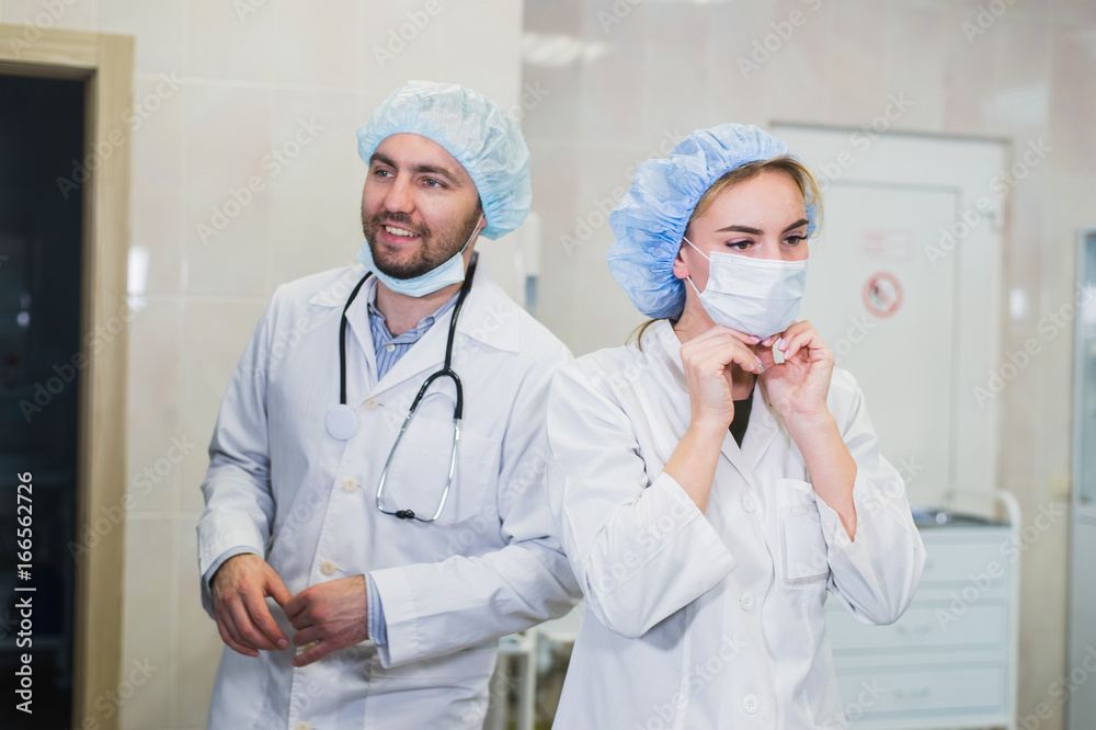 Confident female doctor putting on medical face mask while preparing ...