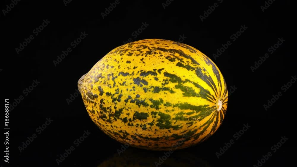 Amazing whole yellow spotted melon, rotating on black background ...
