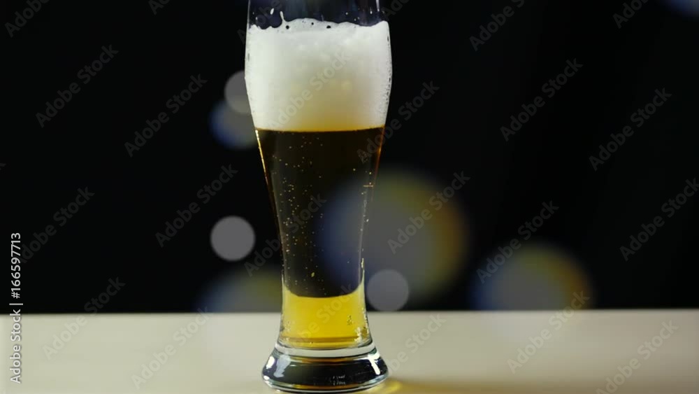 Bubbles and foam move in beer glass. Foam sliding down the glass of ...