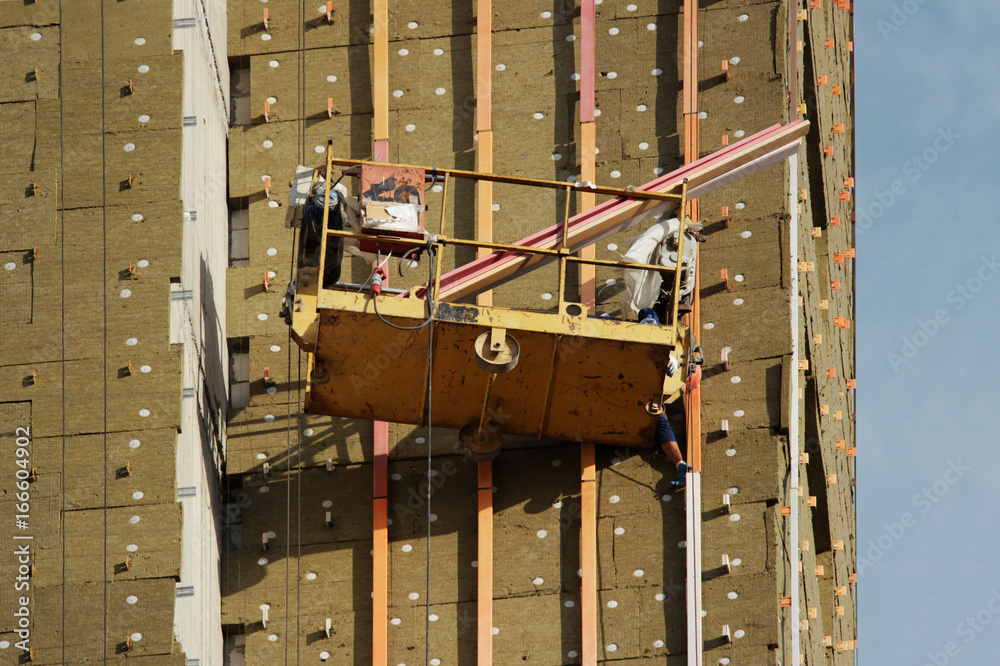Foto de worker in yellow suspended cradle mounts environmental boards ...