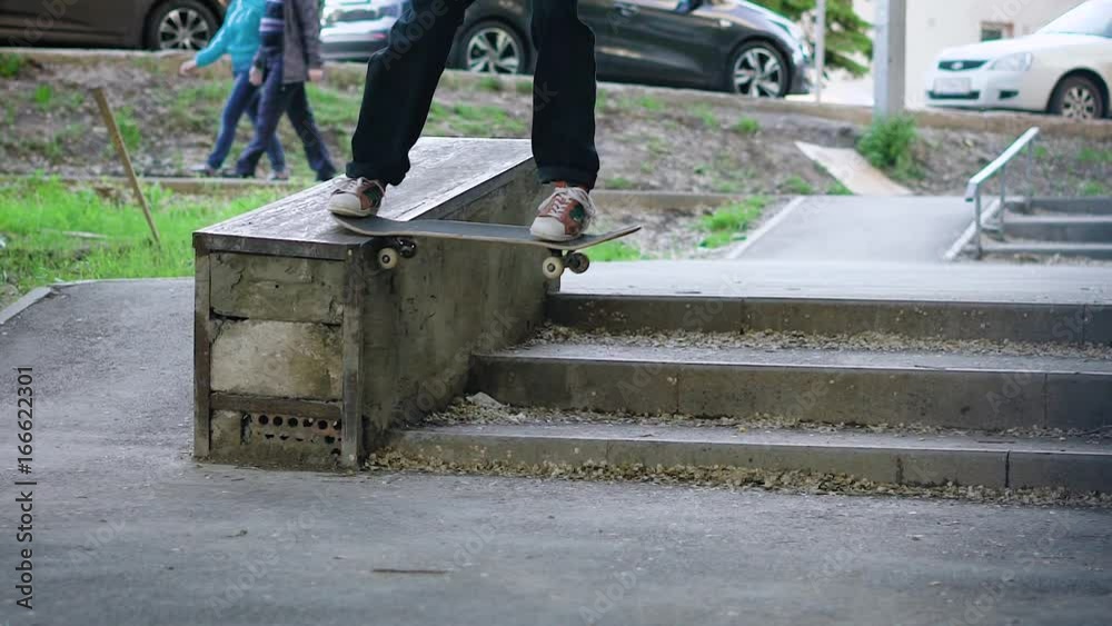 Image of teenager jumping up and doing boardslide on the ledge outdoors ...