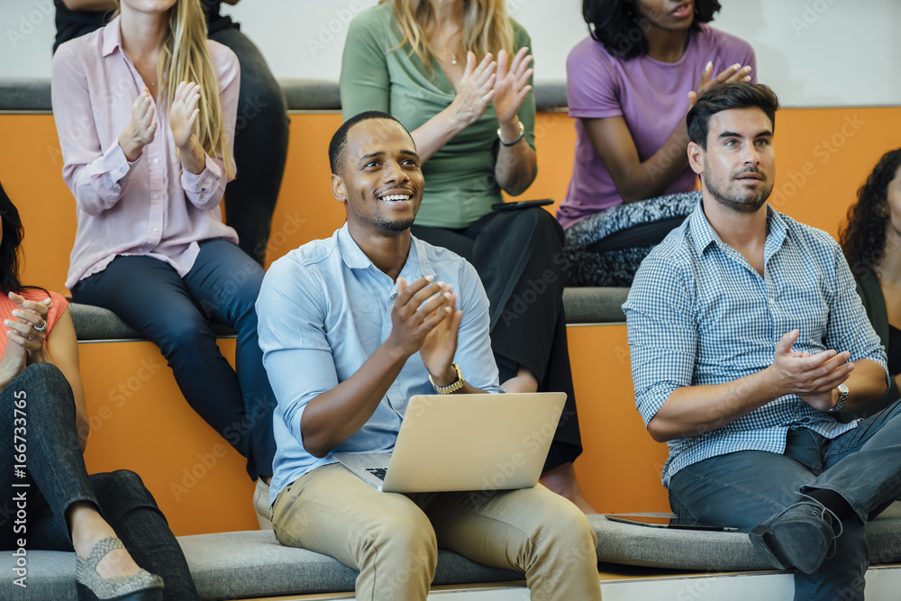 Group of people clapping, enjoying a lecture in a modern auditorium ...