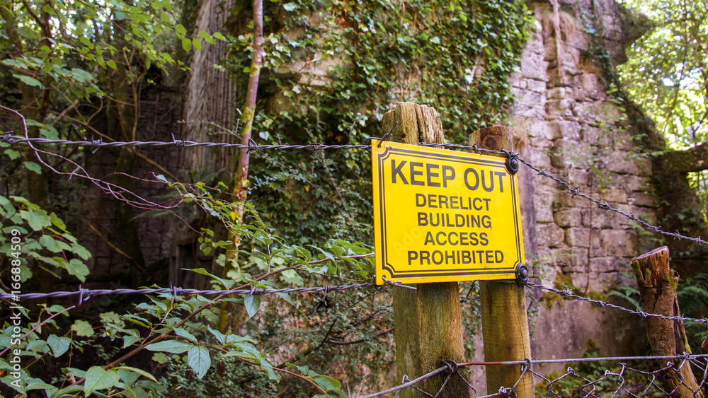 Yellow warning sign with black lettering – KEEP OUT derelict building ...