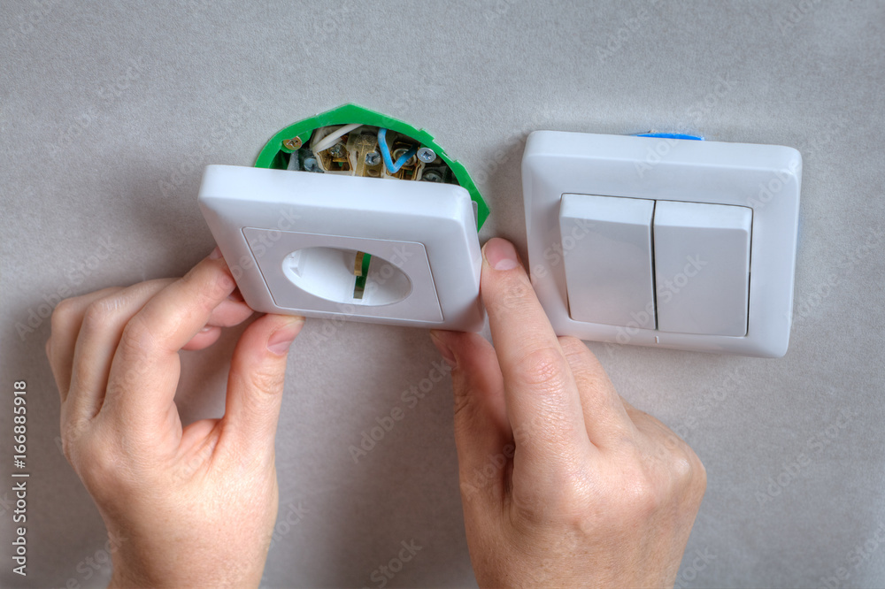 Installing the wall outlet into a wiring box, close-up hands. Stock ...