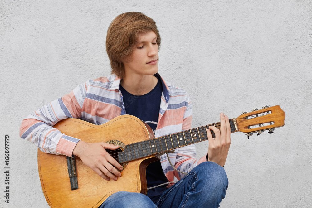 Talented teenage boy with trendy hairdo wearing shirt and jeans holding ...
