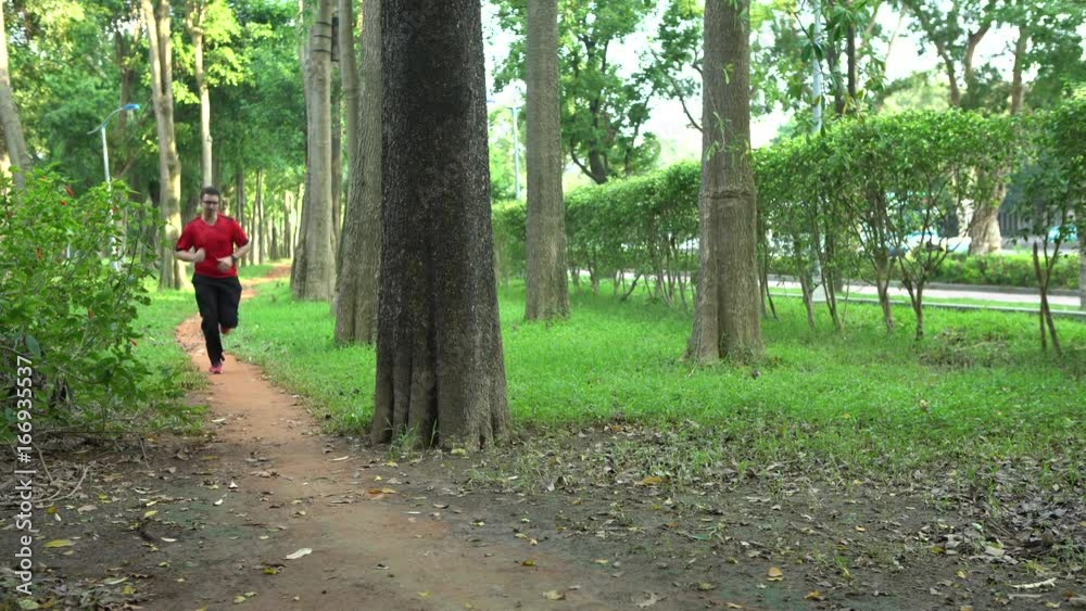 4K Road runner caucasian man running in Taipei city Daan park. Jogging ...