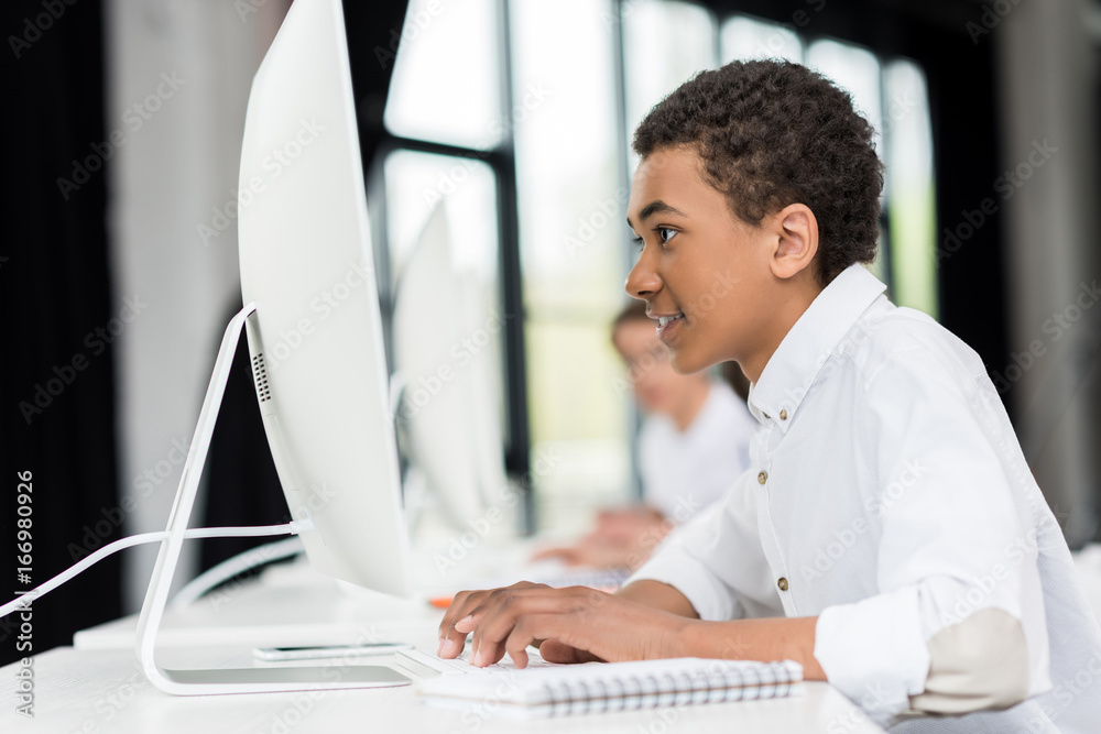 side view of african american teen boy typing on keyboard in front of ...