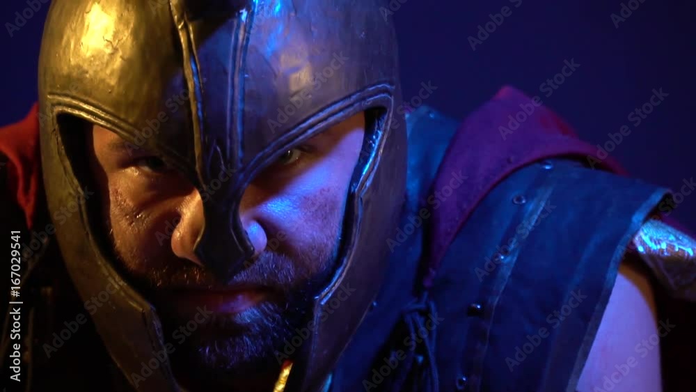 Brutal unshaven Roman gladiator with a scar on his face in a helmet and ...