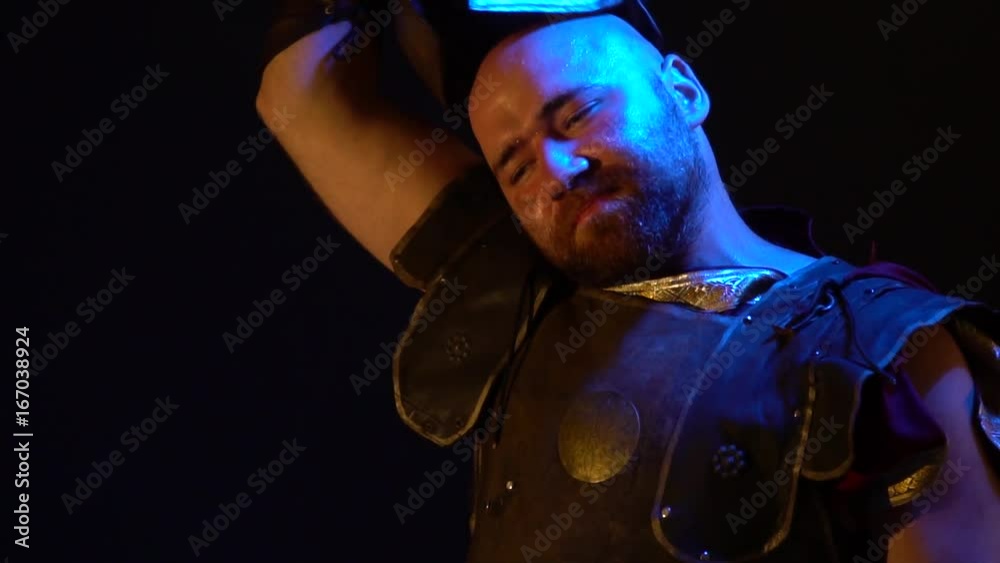 A sweaty Roman gladiator with sword in leather armor with a beard and ...