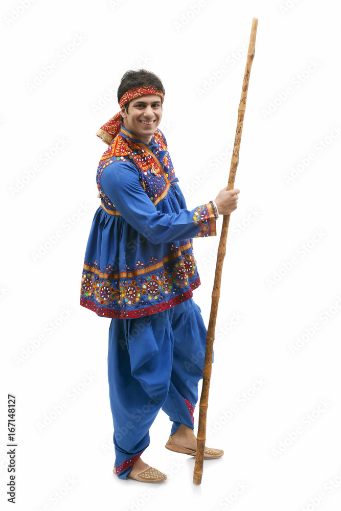 Full length portrait of happy young man in traditional wear holding ...