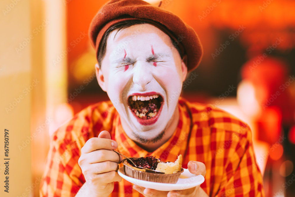 The clown is eating a cake in a cafe and his face is croaking. foto de ...