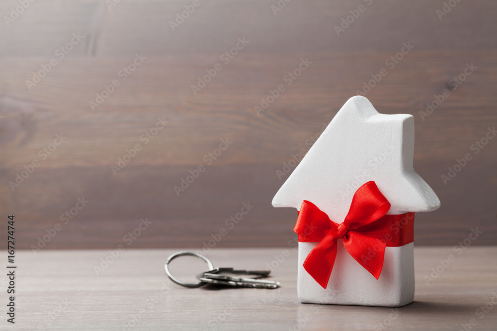 Small white house decorated red bow ribbon with bunch of keys on wooden ...