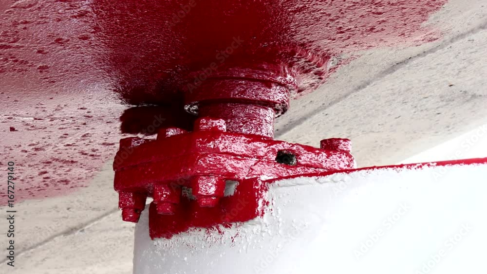 Worker paints metal of ship propeller red color at shipyard in port of ...