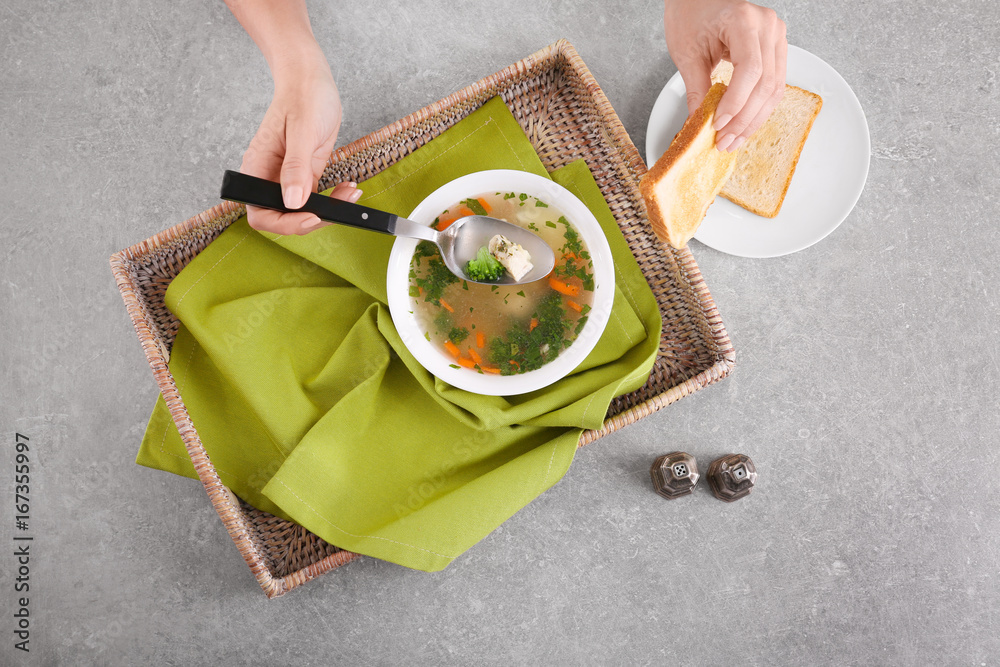 Woman eating homemade chicken soup on wicker tray Stock Photo | Adobe Stock