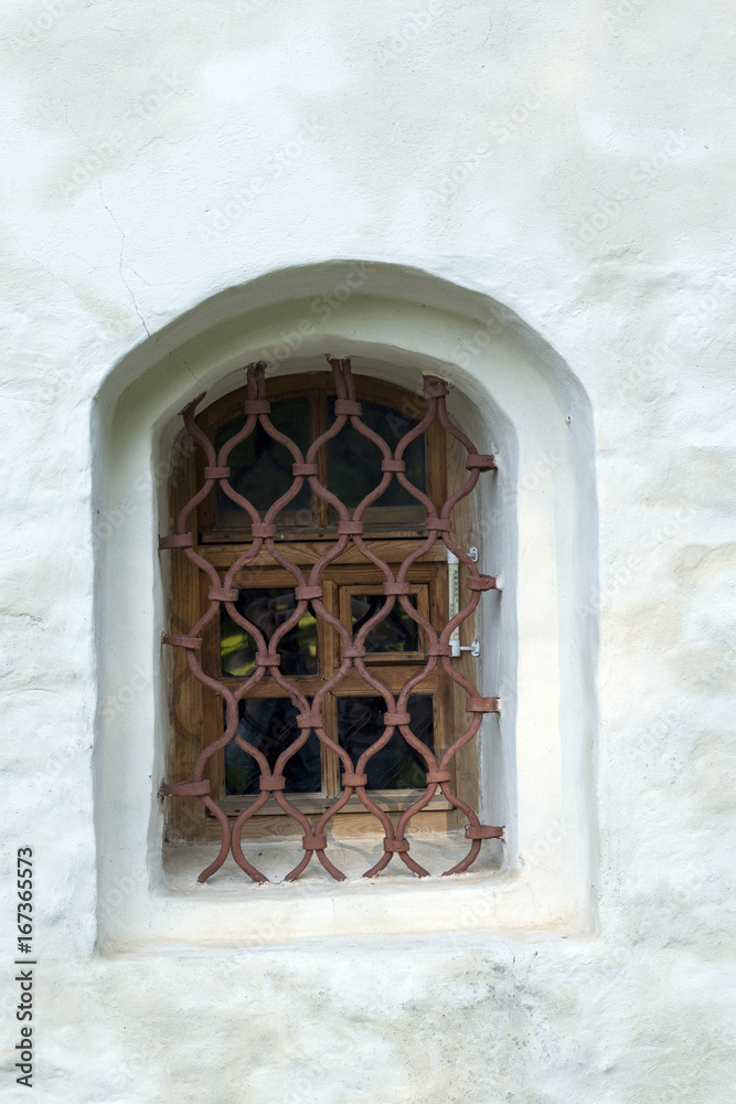 one, 1 small window with bars in white wall, a medieval construction ...