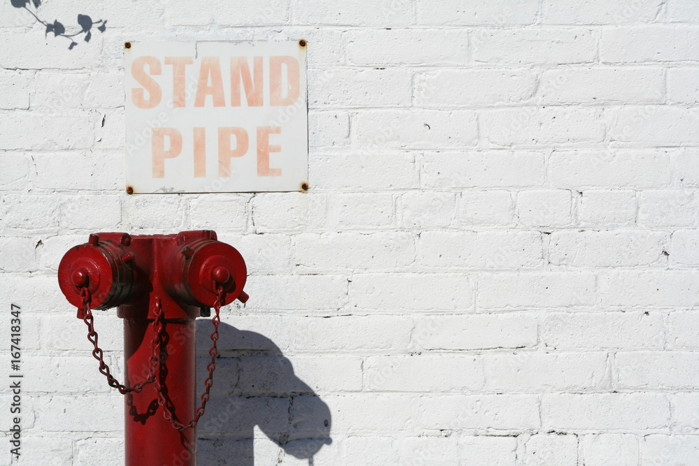 Red Stand Pipe and sign against white brick wall Stock Photo | Adobe Stock