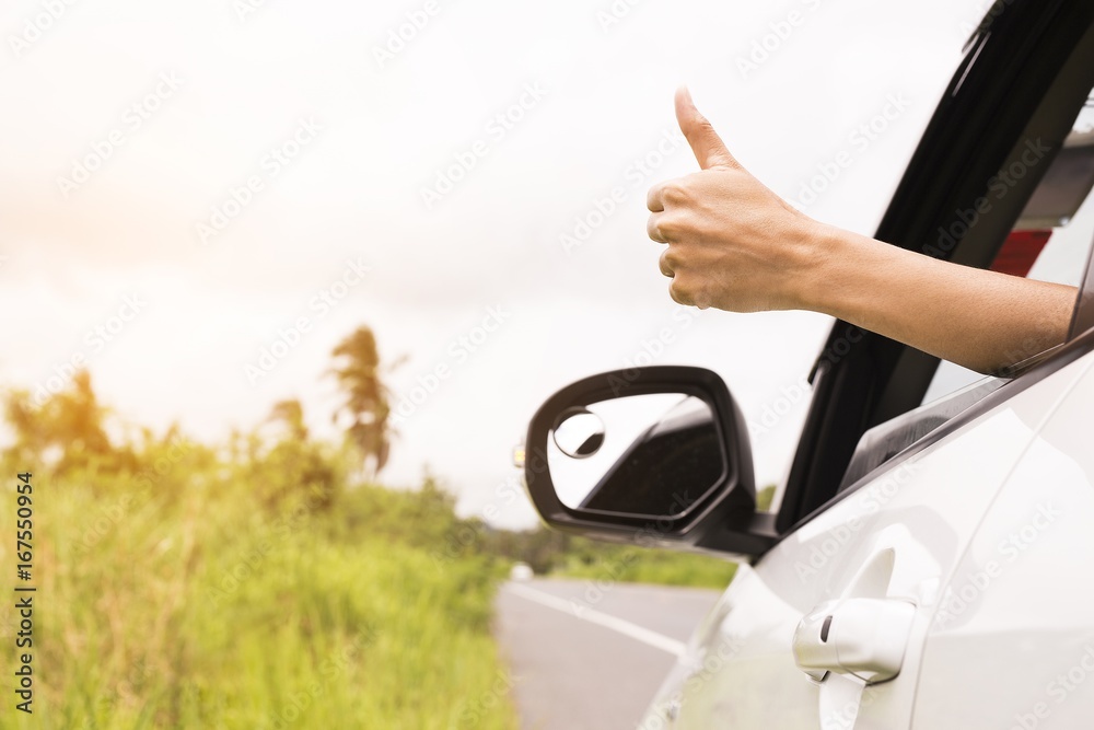 hand giving a thumbs up sign throw the window of a car parked near the ...