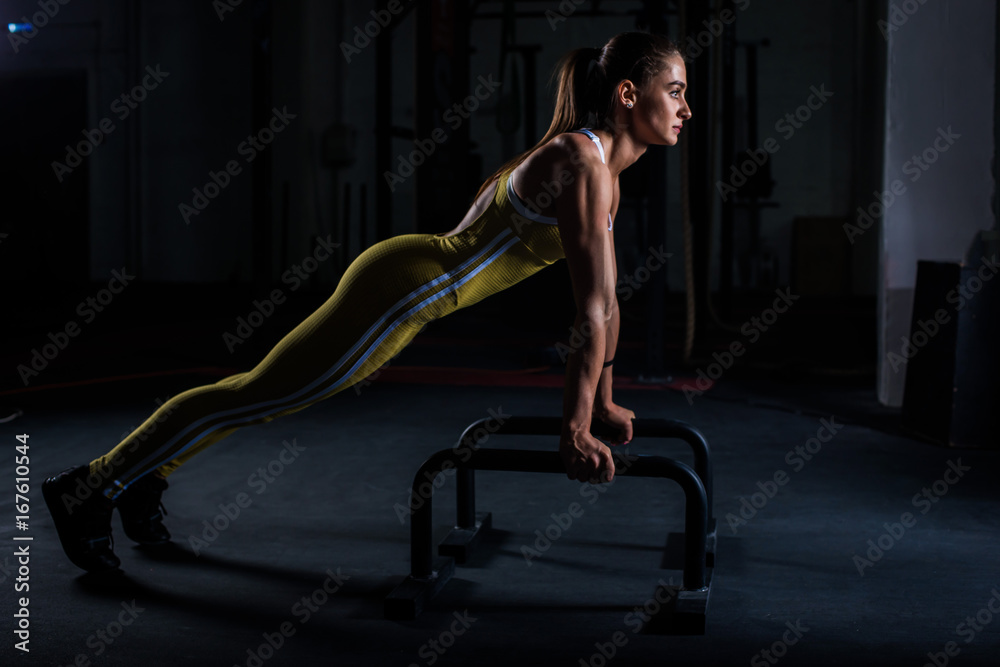 young fit woman doing horizontal push-ups with bars in gym. Stock Photo ...