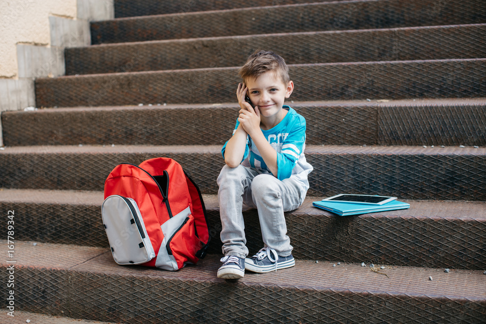 Smiling child making a phone call outside a school. Happy little ...