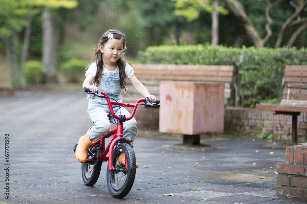 Happy little girl riding a red bicycle Stock Photo | Adobe Stock