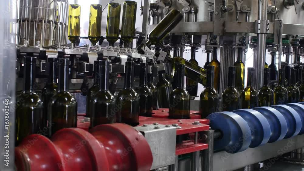 Spill of alcohol wine in glass bottles at the plant. Conveyor belt with ...