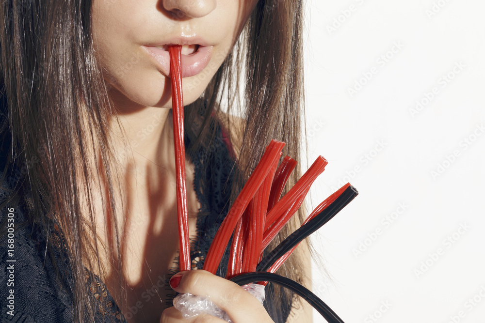 Girl with a bunch of red and black licorice, indoors, over a white ...