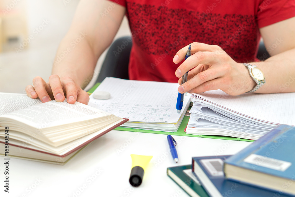 Young athletic man and student studying and writing notes in public or ...