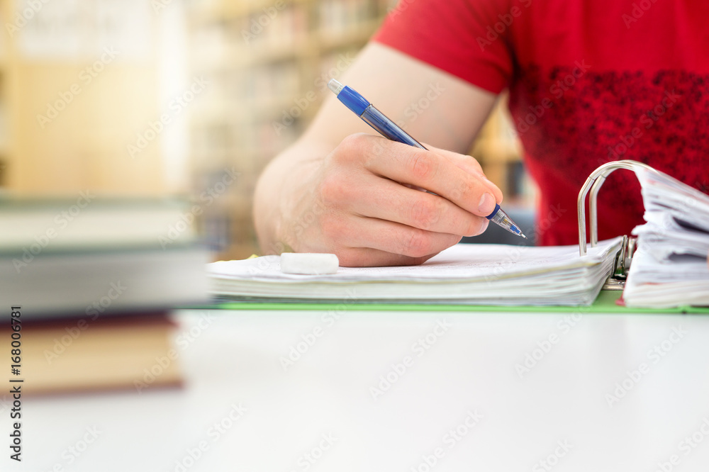 Young athletic man and student studying and writing notes in public or ...
