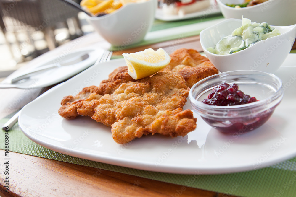 Klassisches Wiener Schnitzel vom Kalb im Biergarten mit Gurkensalat und ...