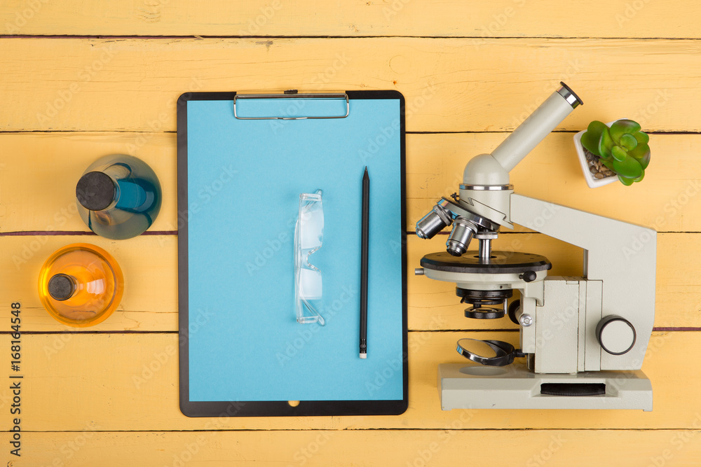 Education and science concept - microscope, blank clipboard, eyeglasses ...