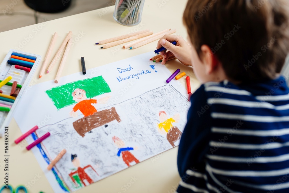Little child draws a pastel drawing of his teacher in school class ...