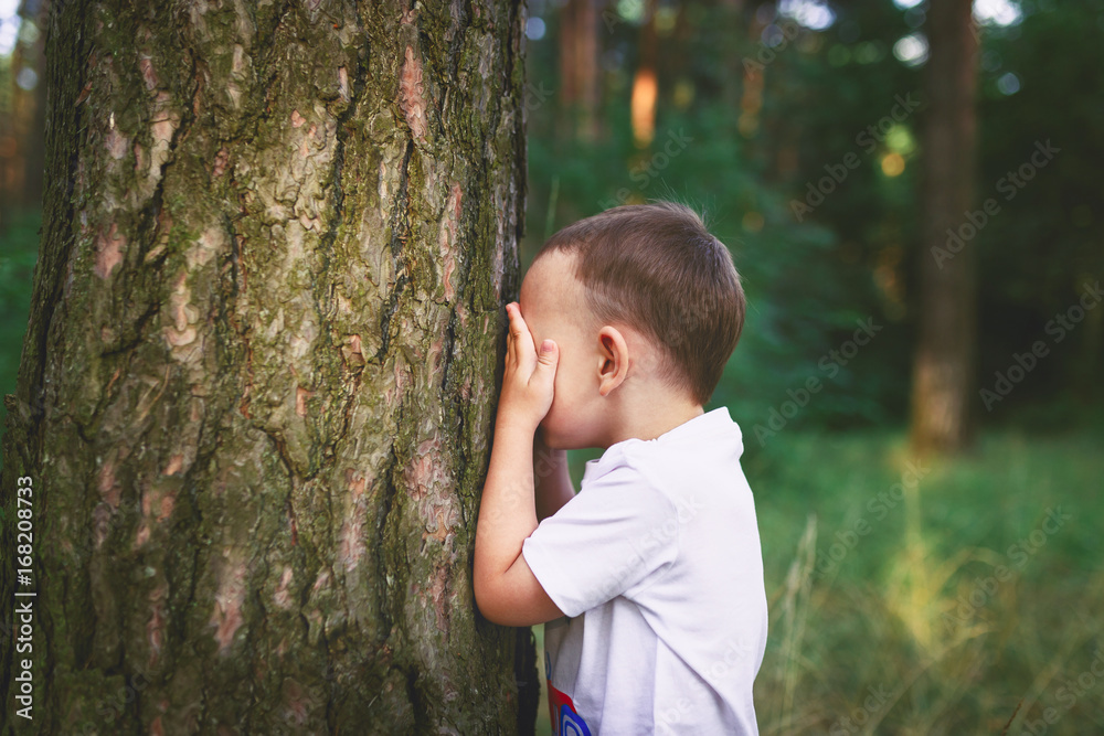 Little Caucasian boy closing his face with hands as if playing hide and ...