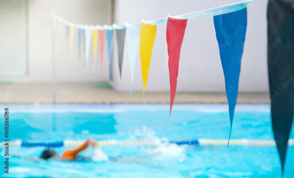 Flag strip over swimming pool with motion blurred of active children ...