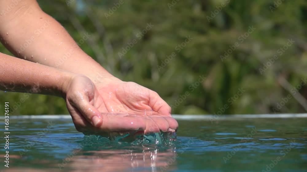 SLOW MOTION, CLOSE UP, DOF: Woman scooping smooth pool water into her ...