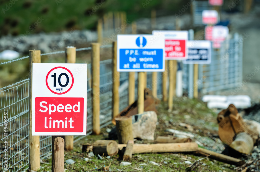 Signs along the path of a construction site including Speed Limit, PPE ...