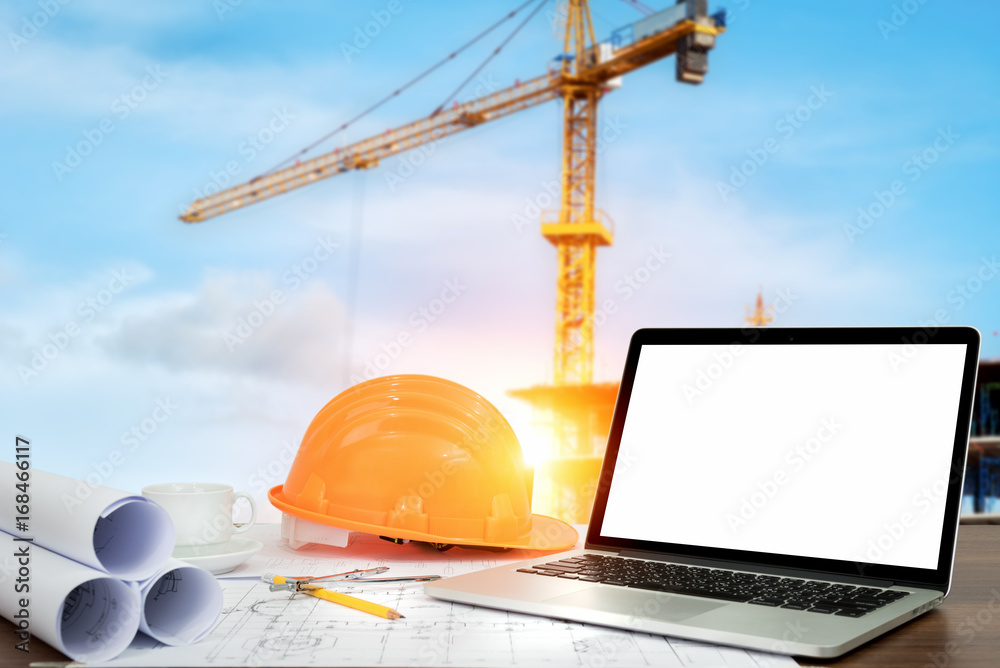 safety helmet and Laptop with blank screen on table over building ...