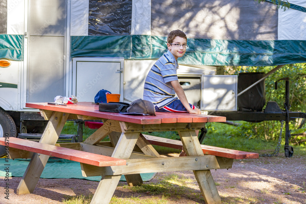 Foto de Young preteen boy sitting on picnic table next to family ...