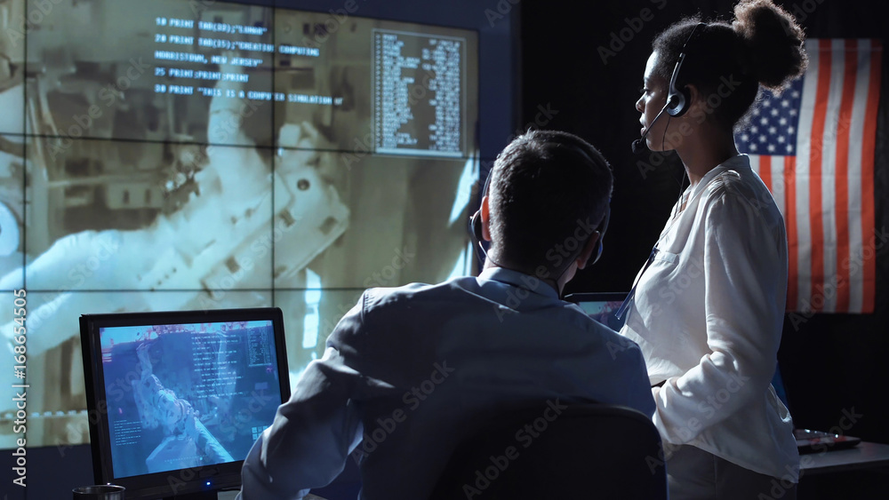 Back view of man and woman in space flight control center. Сontrols the ...