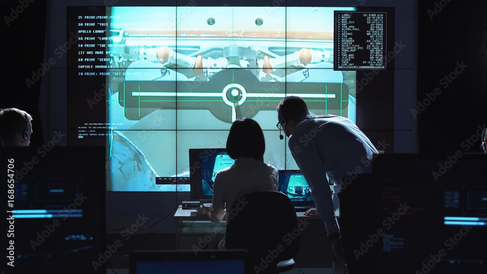 Back view of man and woman in space flight control center. Docking of ...