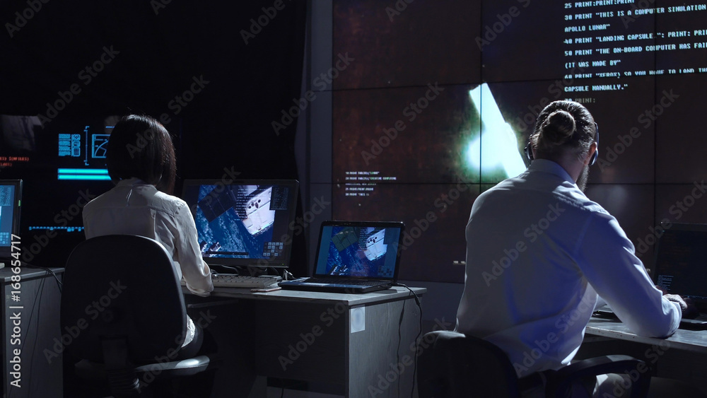 Back view of man and woman in space flight control center. Docking of ...