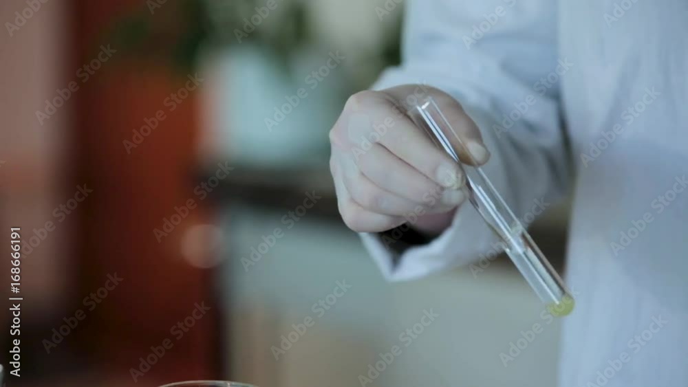 Scientist hand pouring a chemical solution from a laboratory glass test ...