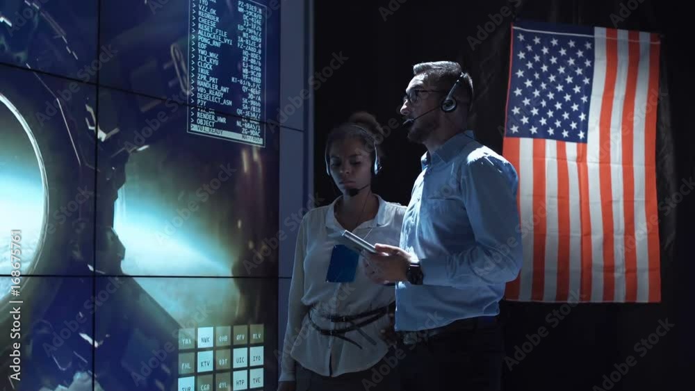 Woman and man monitoring in dark room of space mission moon landing ...