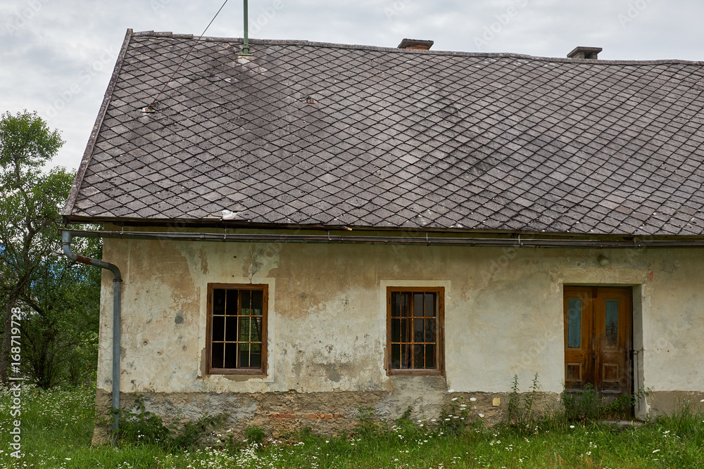 Old rotten windows and door in a ruined house facade in a messy ...