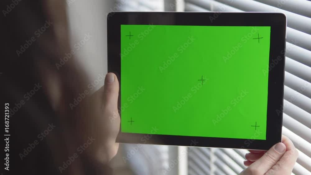 Woman wear in black sweater is holding a tablet pc with green screen ...