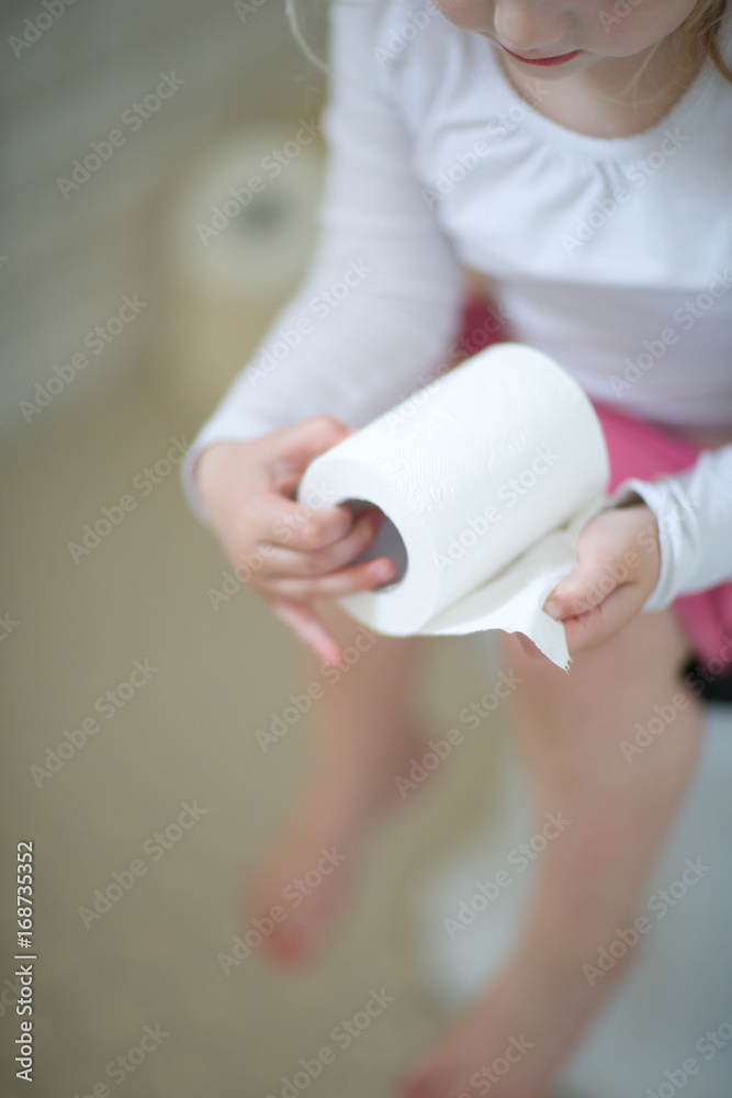 little girl holding tissue paper in toilet. childhood, toilet paper ...