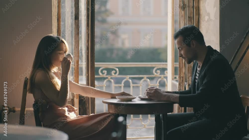 Loving man gently kissing a modest girl in a cafe. Romantic kiss a ...