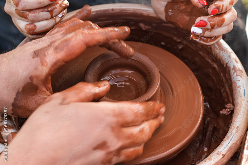 Teaching pottery. A carftman's hands guiding a child hand, showing how ...